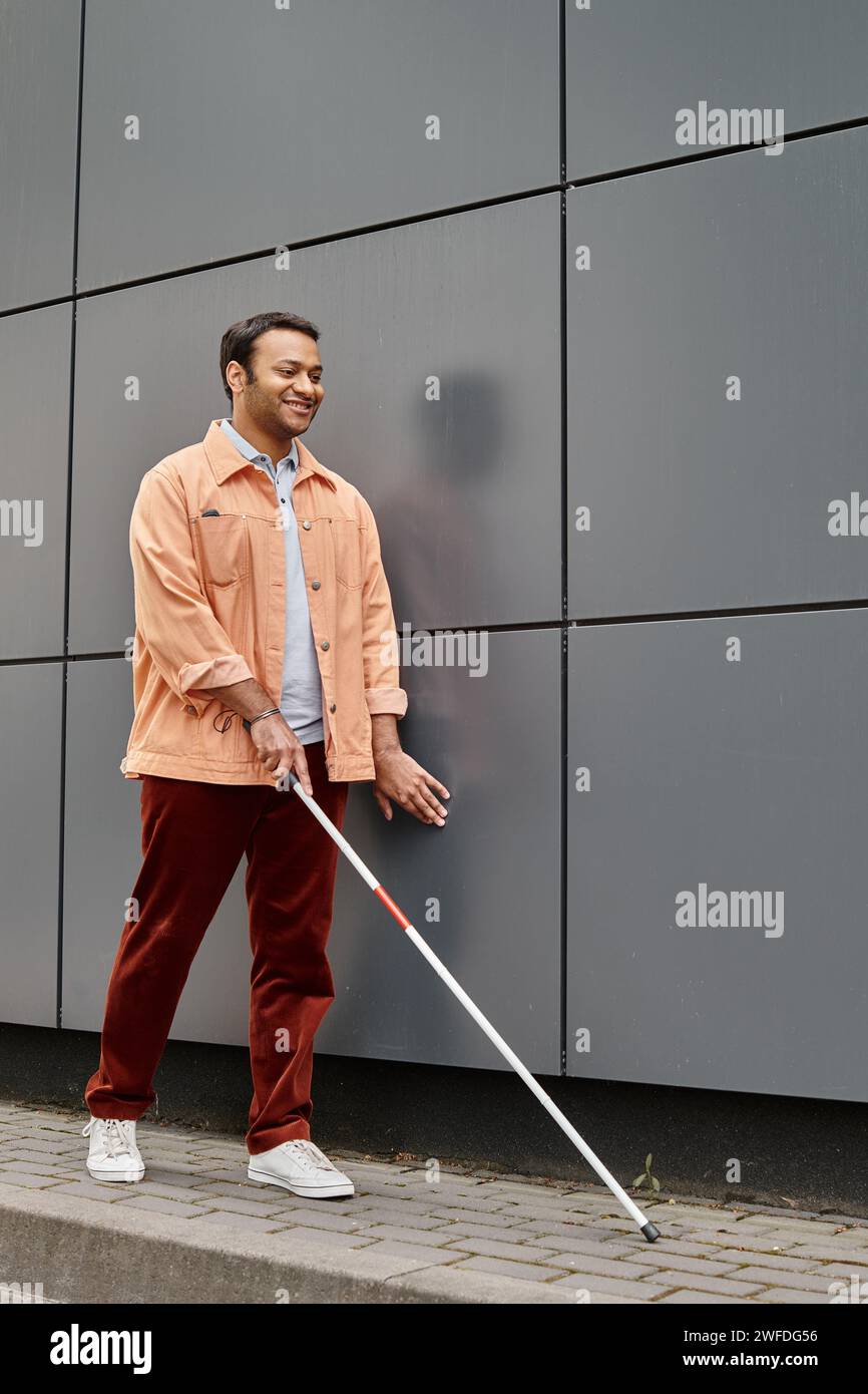 joyful indian blind man in orange jacket with helping stick walking ...