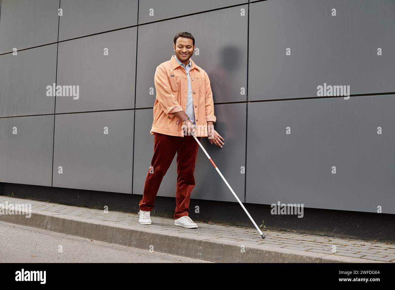 merry indian blind man in orange jacket with helping stick walking with ...