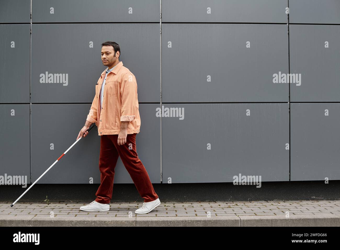 handsome indian blind man in orange jacket with helping stick walking ...