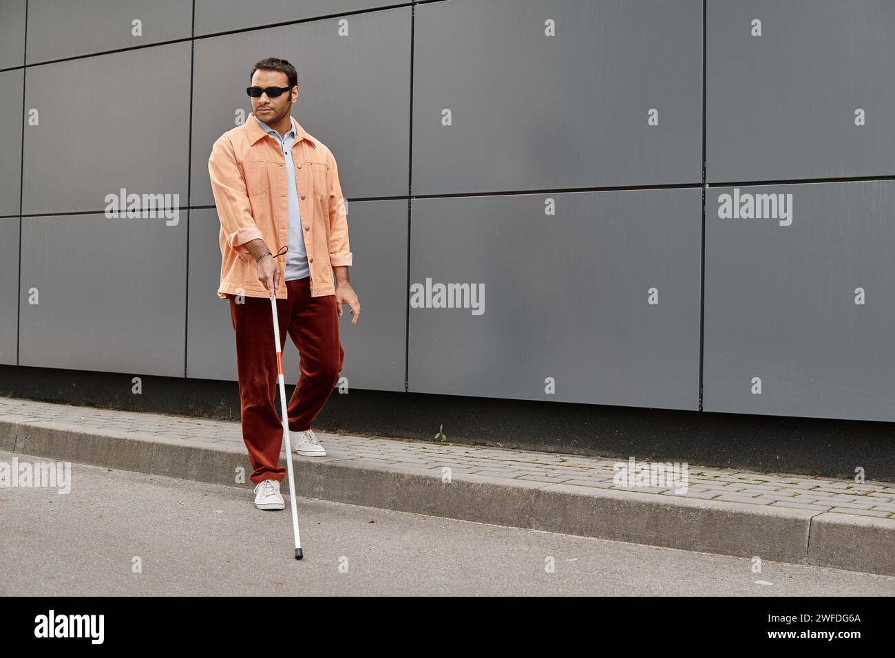 jolly indian blind man in orange jacket with walking stick and glasses ...