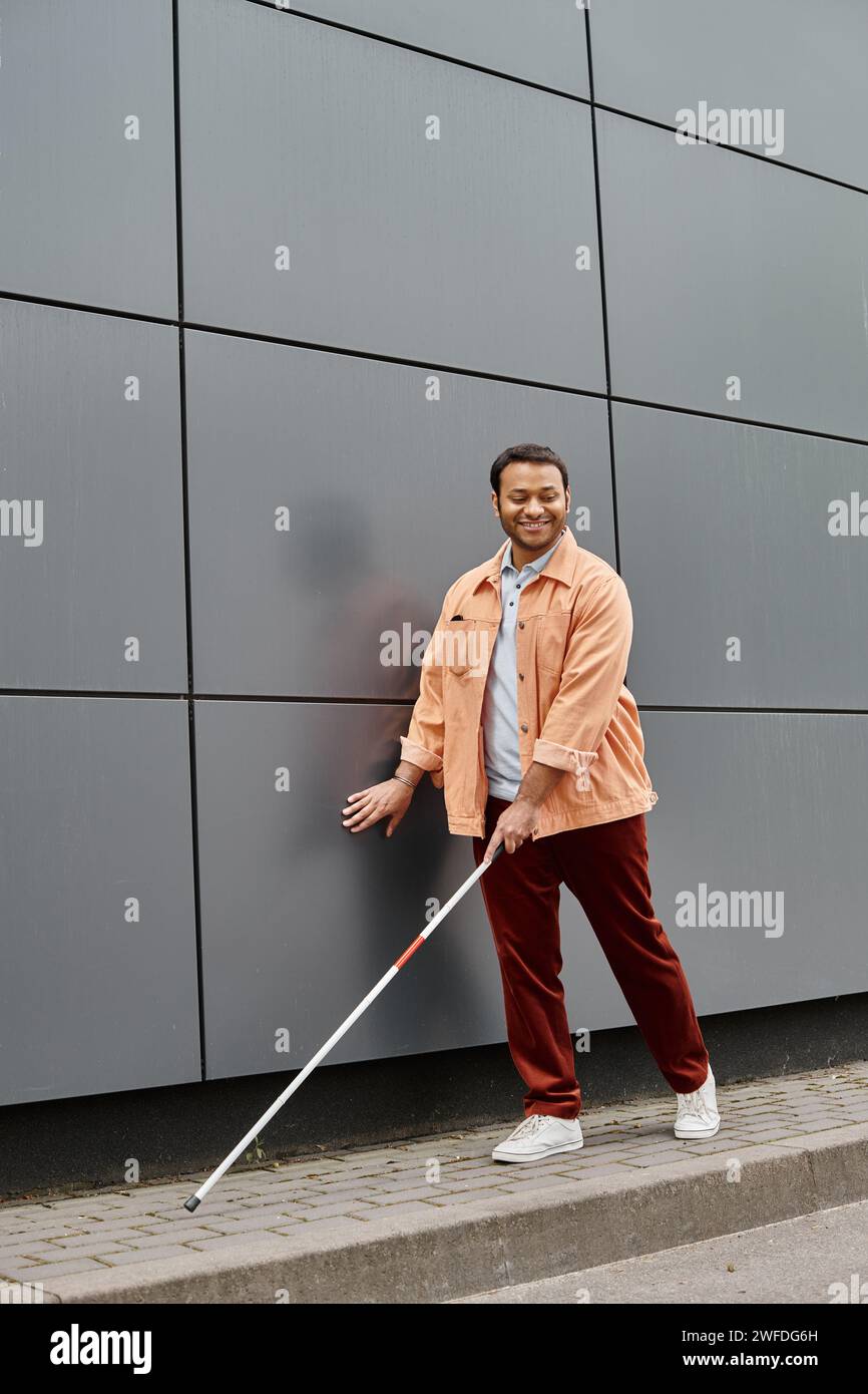 joyous indian blind man in orange jacket with helping stick walking ...