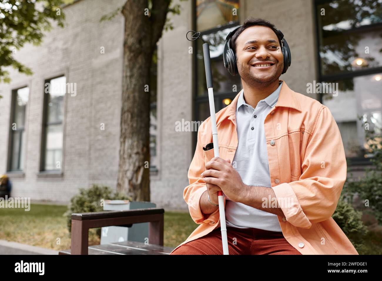 jolly indian man with blindness in headphones with walking stick ...