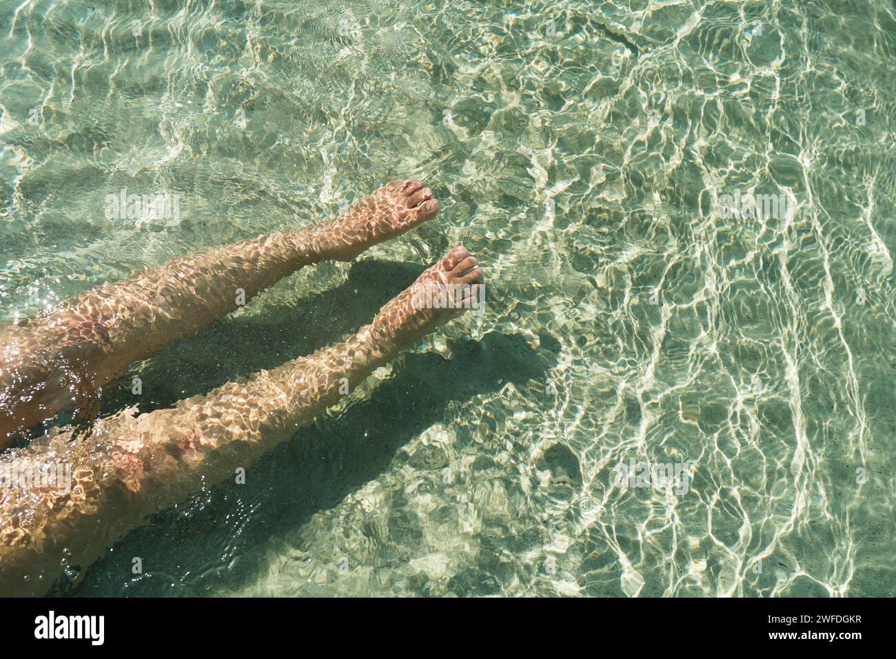 Female legs in crystal clear water on a beach with sandy. Legs dipped ...