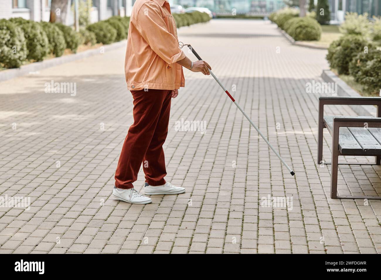 cropped view of indian blind man in orange vibrant jacket using walking ...