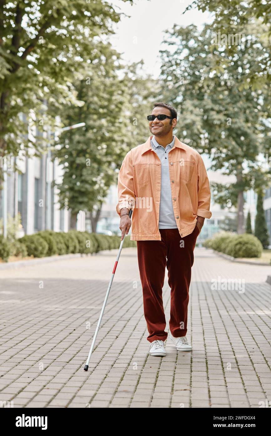 joyful indian blind man with glasses and walking stick in orange vivid ...