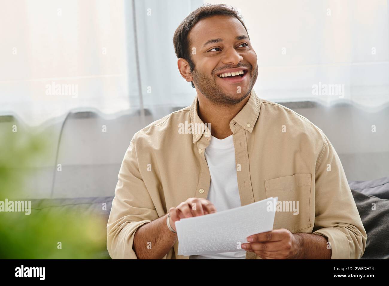 cheerful indian blind man in casual comfortable attire sitting on sofa ...