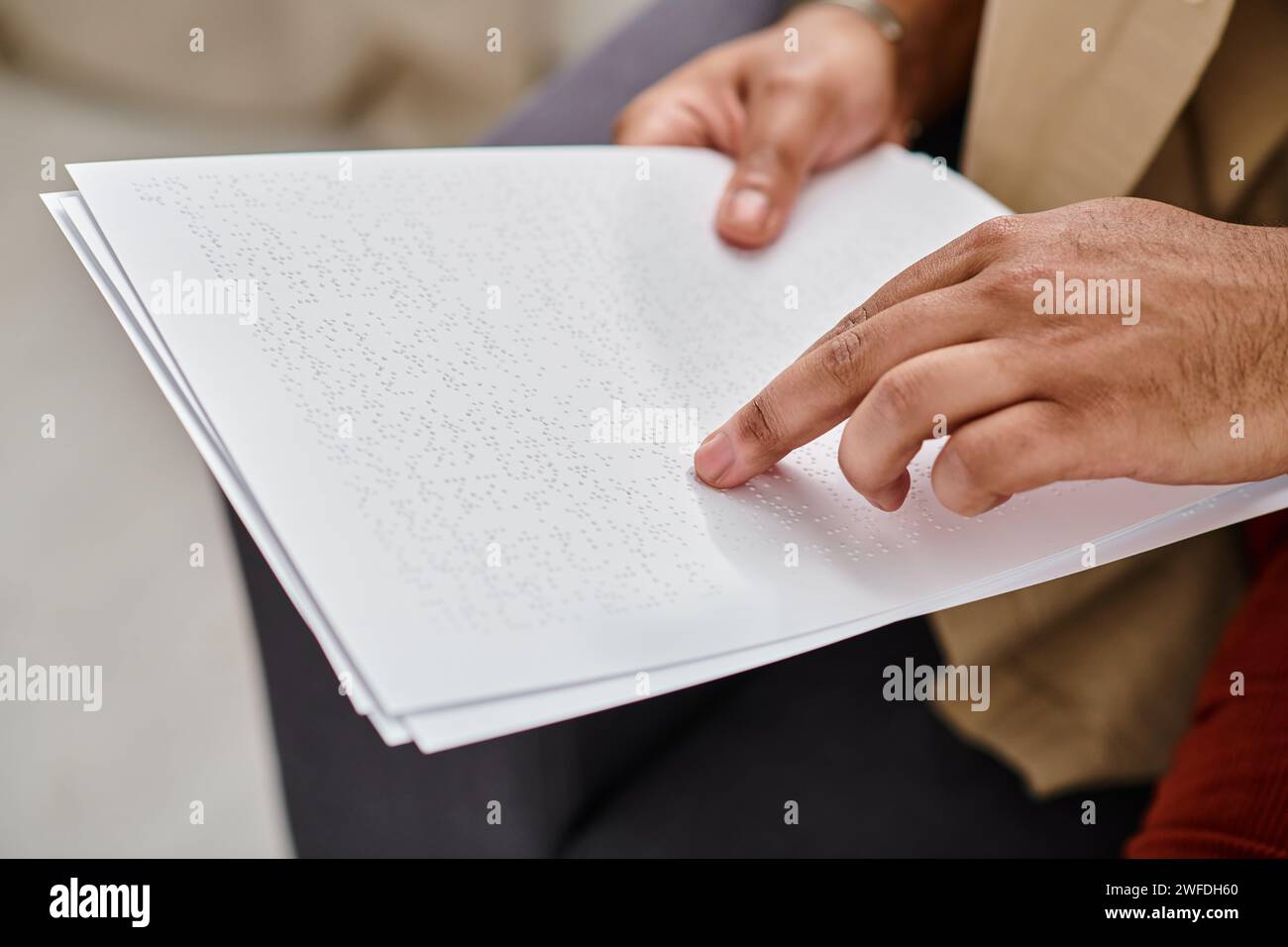cropped view of indian disabled man in casual attire sitting on sofa ...