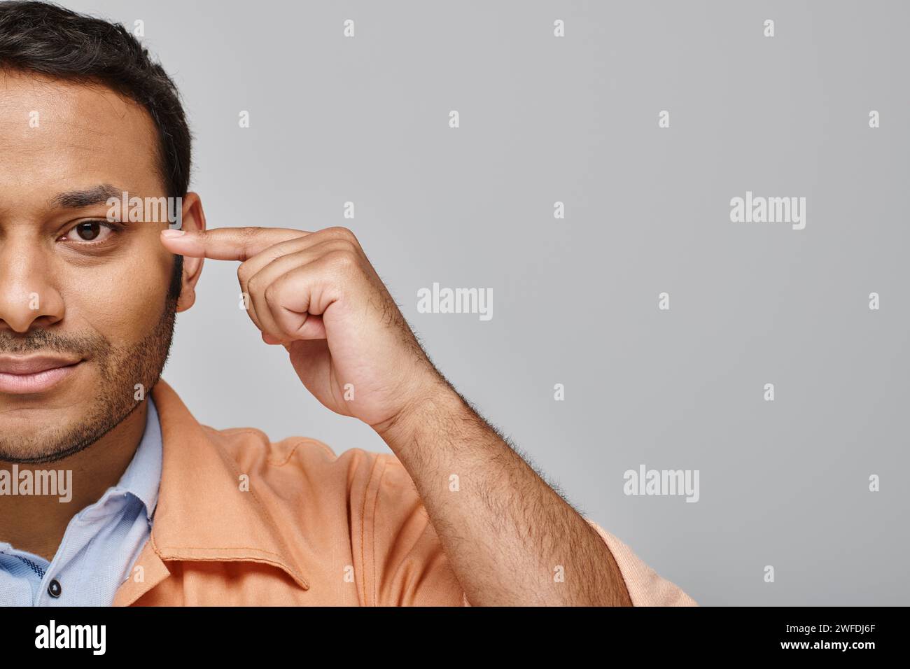 handsome jolly indian man in orange vibrant jacket posing with finger ...