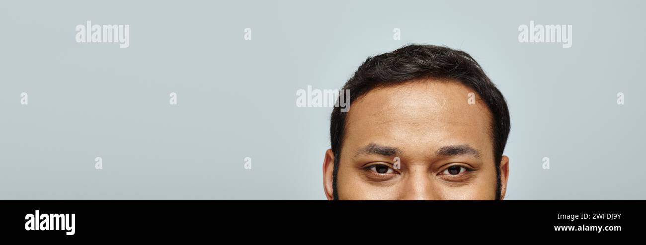 handsome indian male model looking straight at camera with gray wall on ...