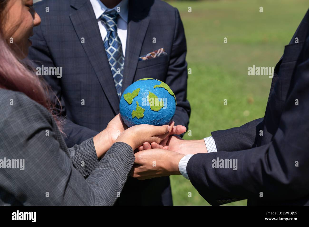 Group of business people hold planet Earth globe together as Earth day concept. Mission to save ...