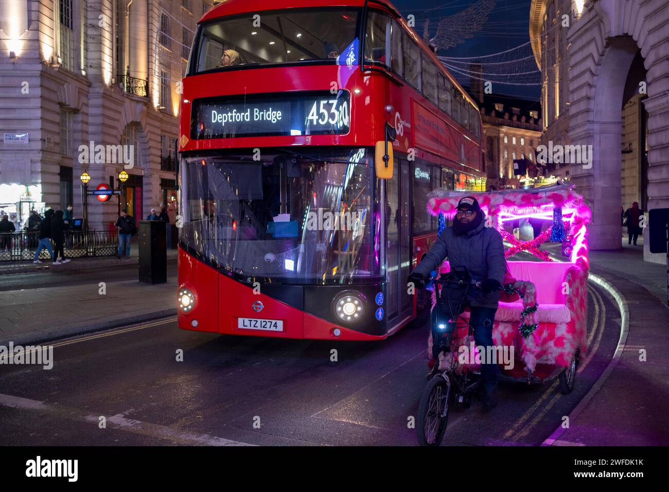 Cycle taxi rider waiting alongside a double decker bus at the traffic ...