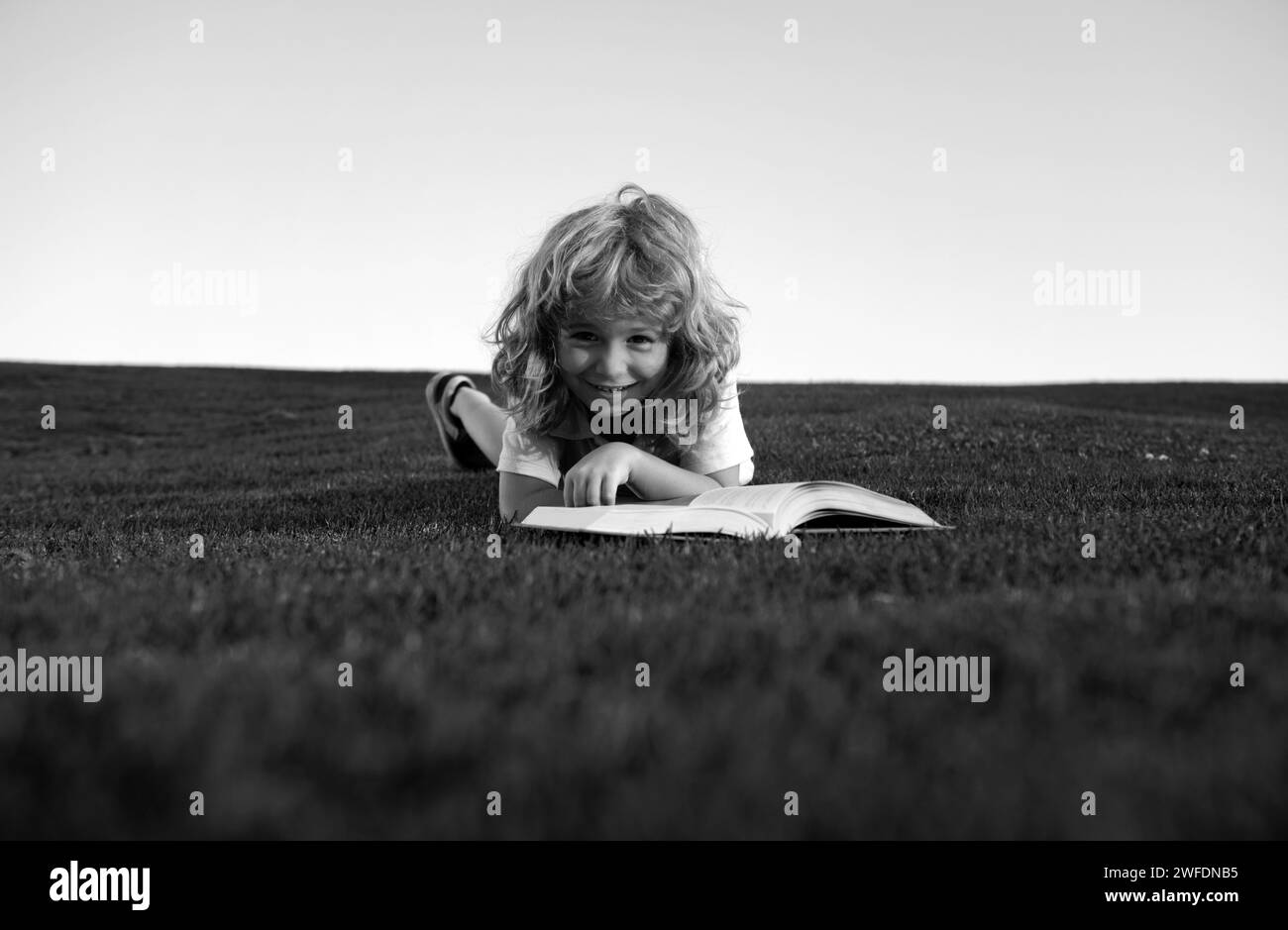 Smart kid boy reading book in park on green grass lawn outdoor Stock ...