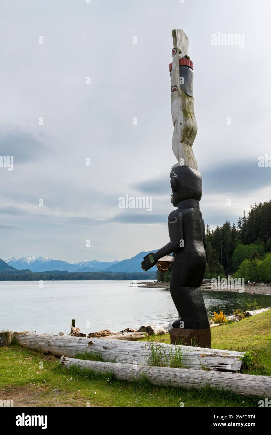 A totem overlooks the beach and strait offshore, with mountains beyond ...