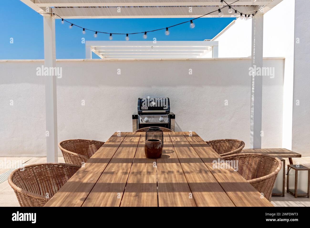 a large wooden dining table and small barbecue on rooftop terrace in ...