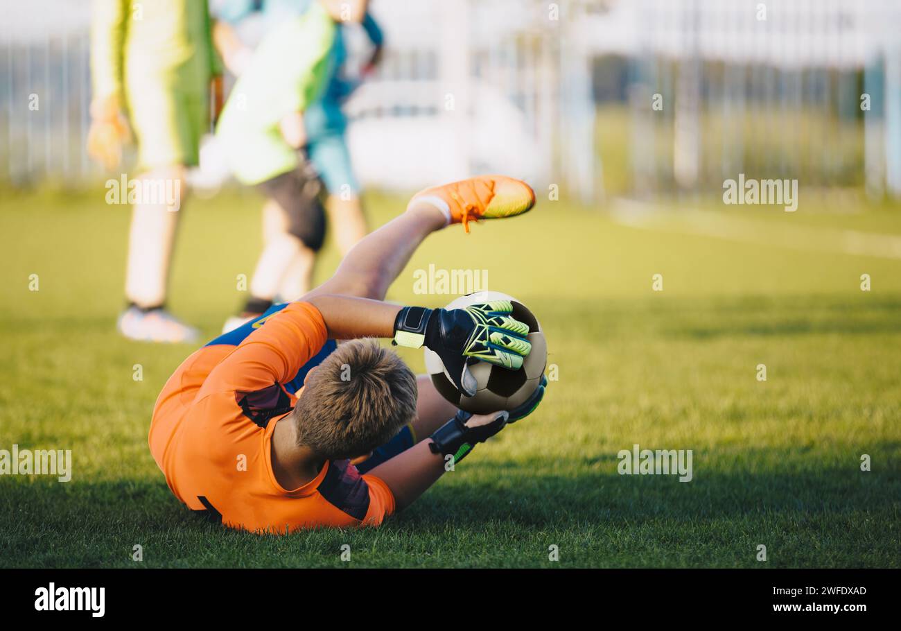 School boy as a soccer goalie catching football ball during a ...