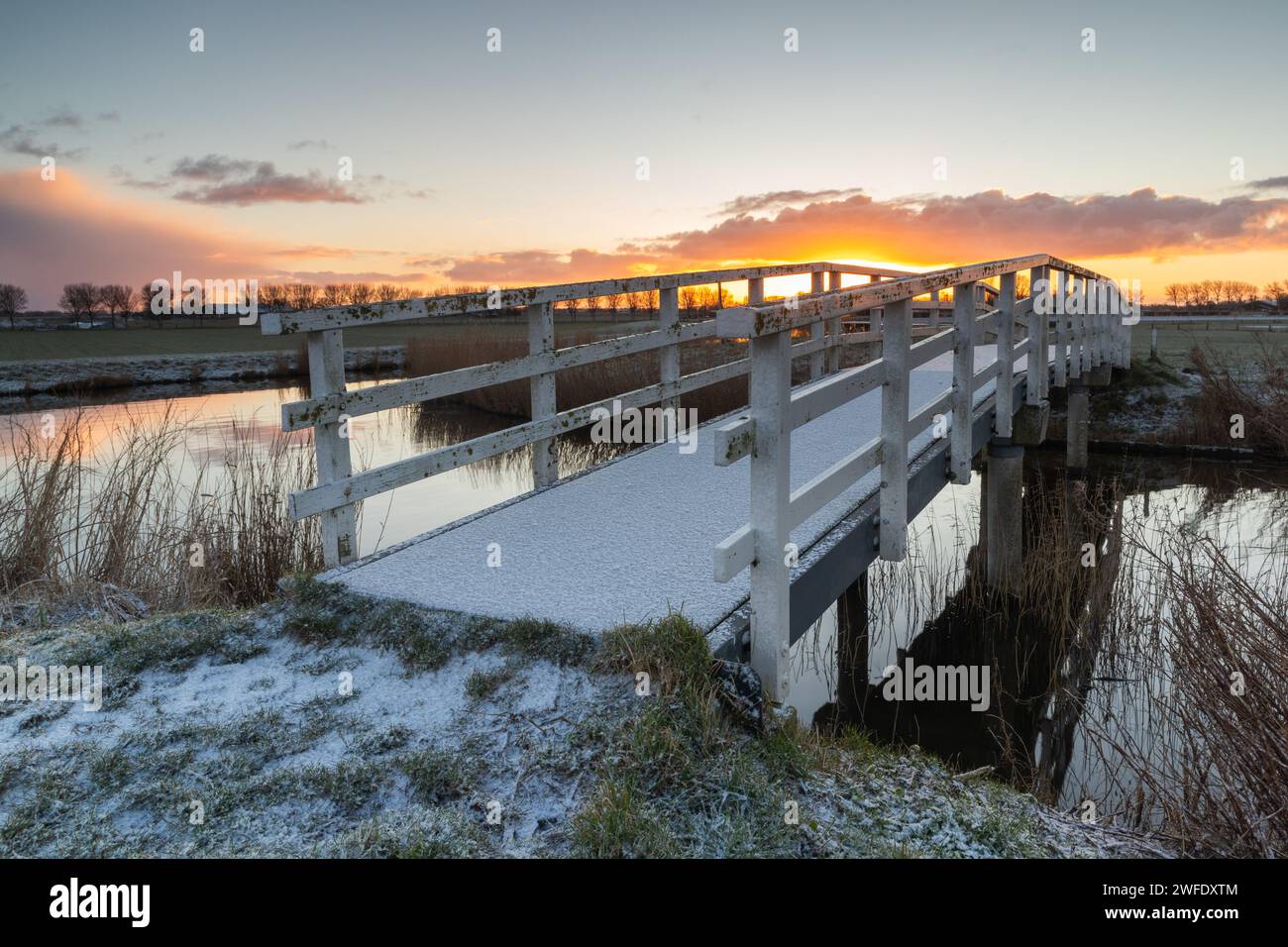 White wooden arched bridge with a layer of snow in the morning sun ...