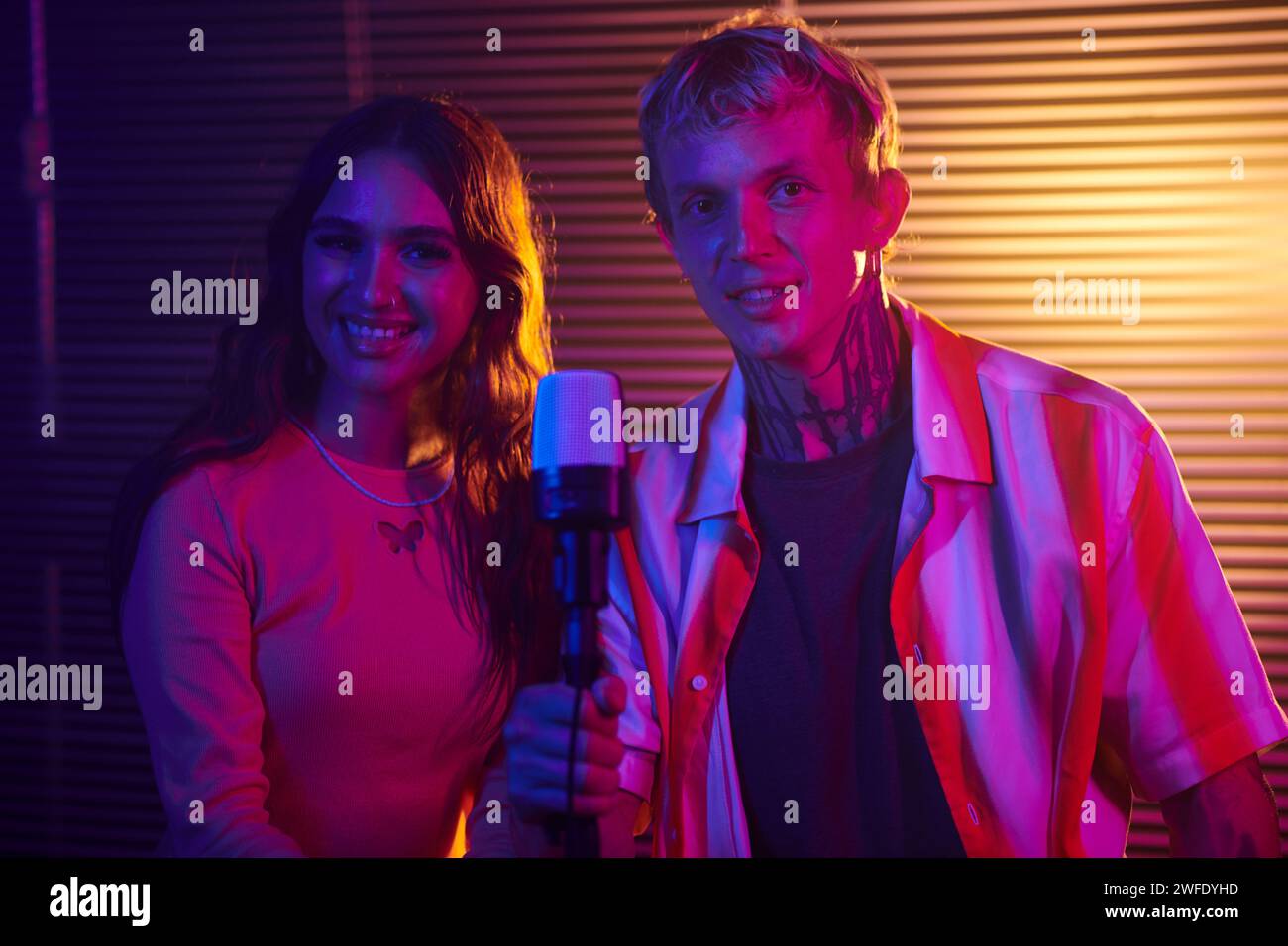 Portrait of smiling duet singing song in microphone at party Stock ...