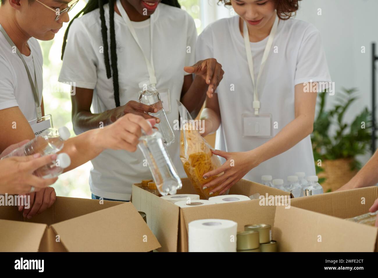 Charity organization workers putting packages of macaroni and bottled ...