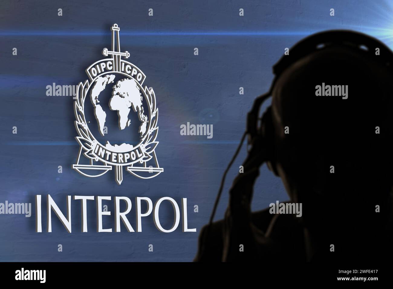 Silhouette of secret agent wearing headphones against Interpol emblem ...