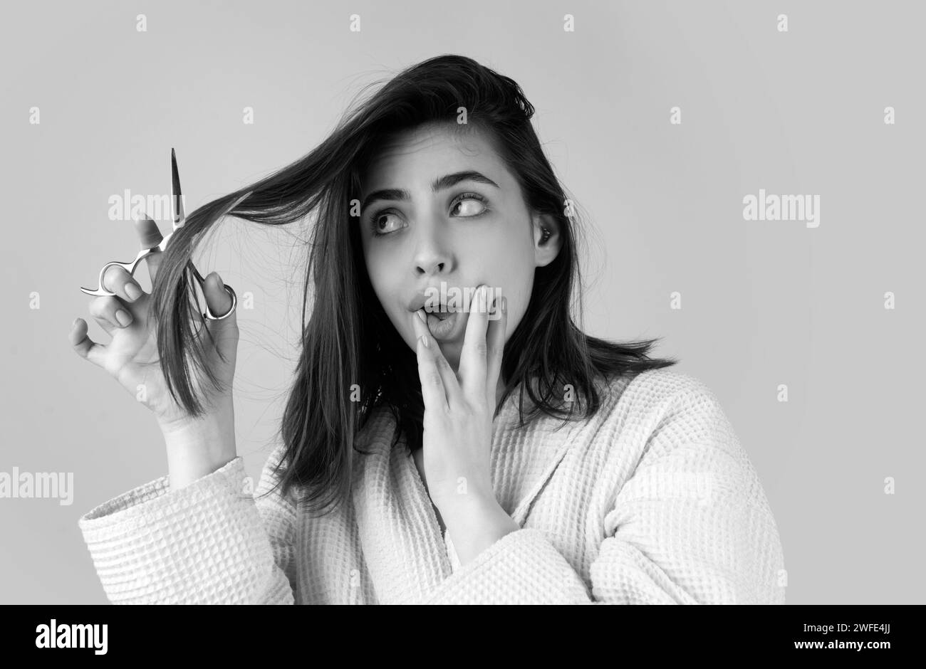 Sad woman having her hair cut with scissors. Beautiful woman in panic ...