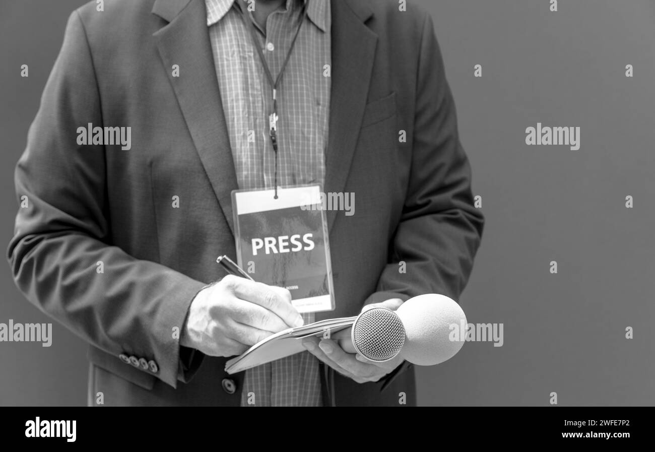 Male journalist at news conference or media event, holding microphone ...