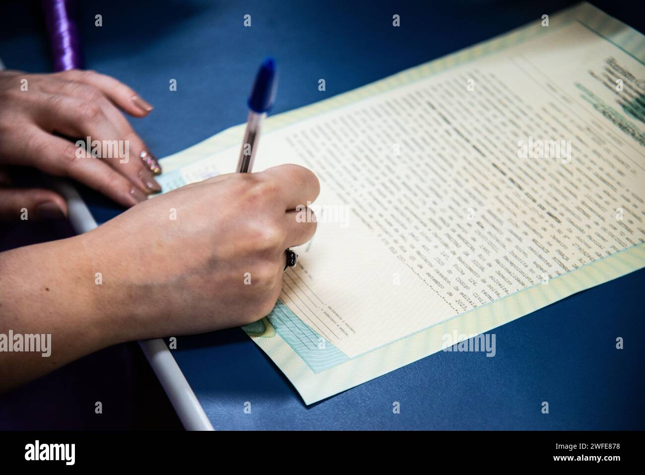 A blue pen glides across the paper as a person writes in the palm of ...