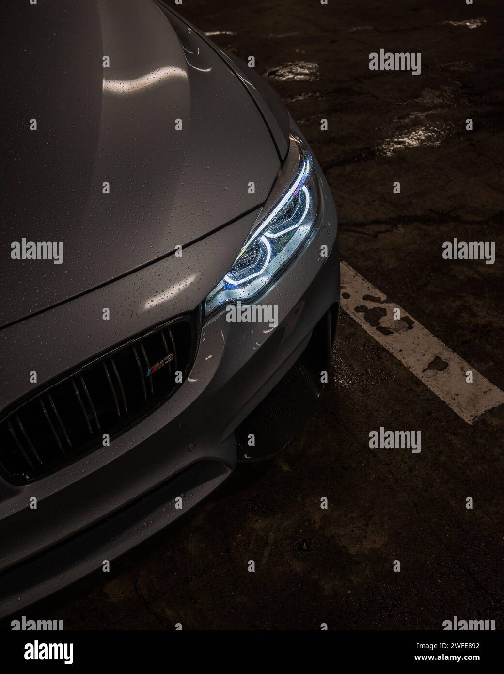 A close-up shot of a sleek AMG car with rain droplets parked in dim ...