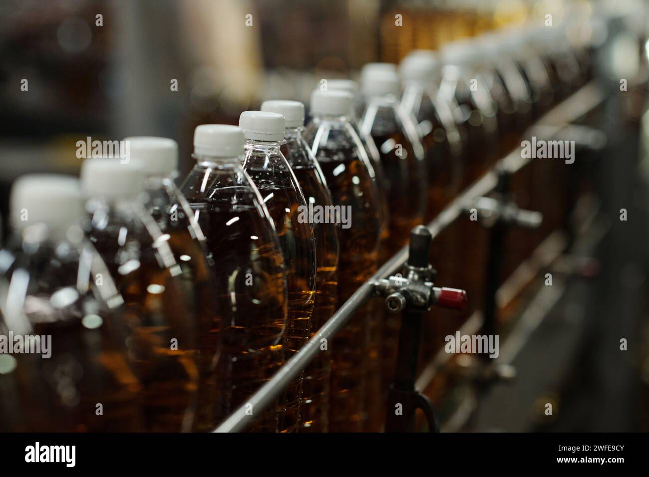 Row of packed plastic bottles containing soda with white caps moving ...