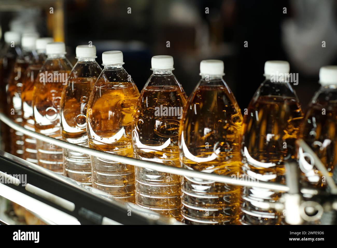 Row of transparent plastic bottles with soda or lemonade packed with ...