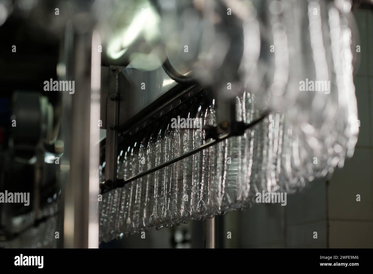 Focus on row of empty clean plastic bottles rotating in belt conveyor ...