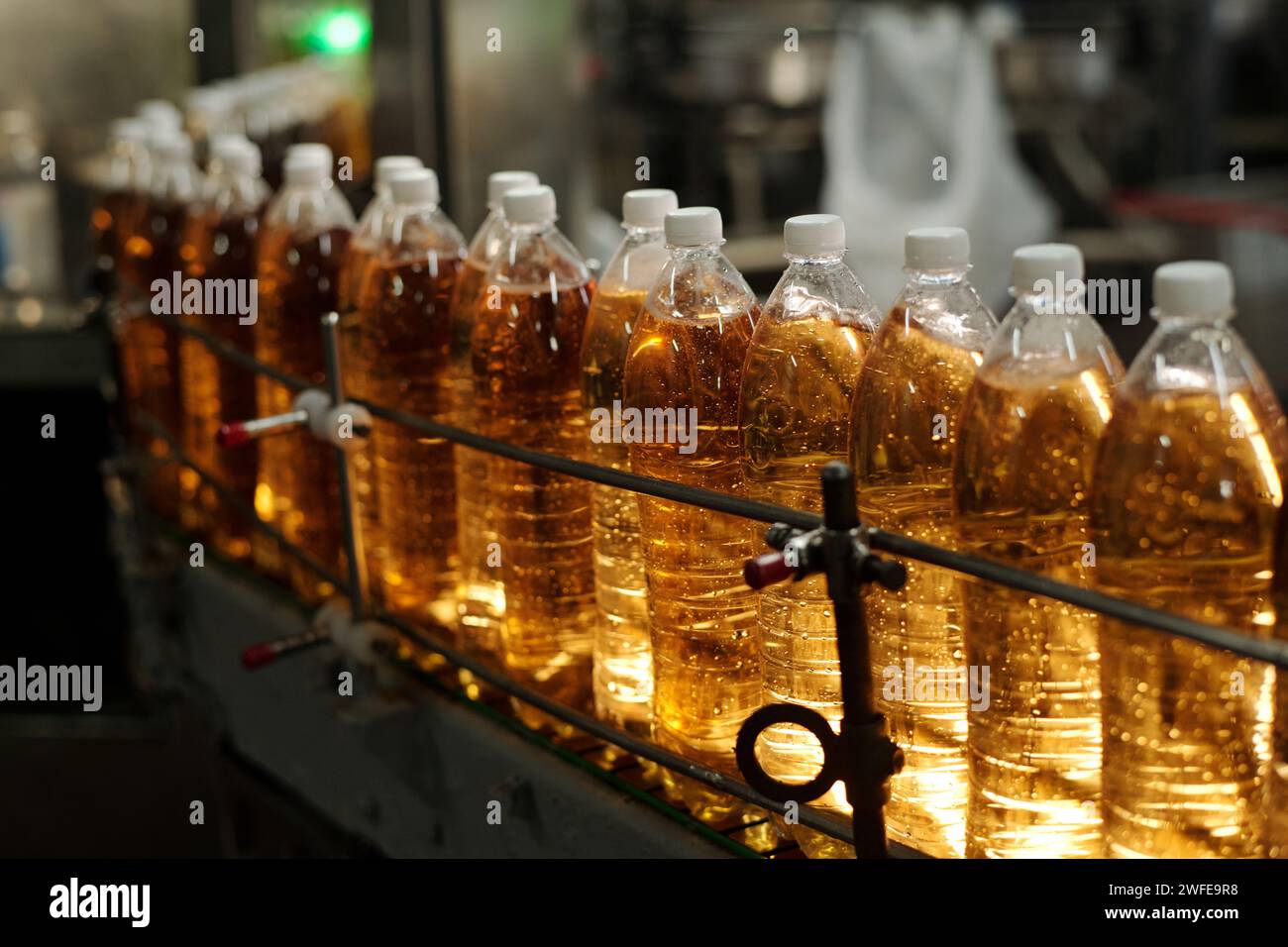 Group of capped bottles with carbonated beverage moving along automated ...