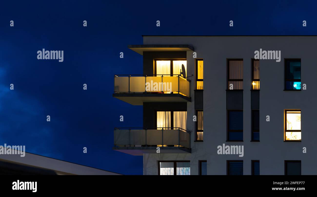 Balconies and windows of a residential building illuminated at night ...