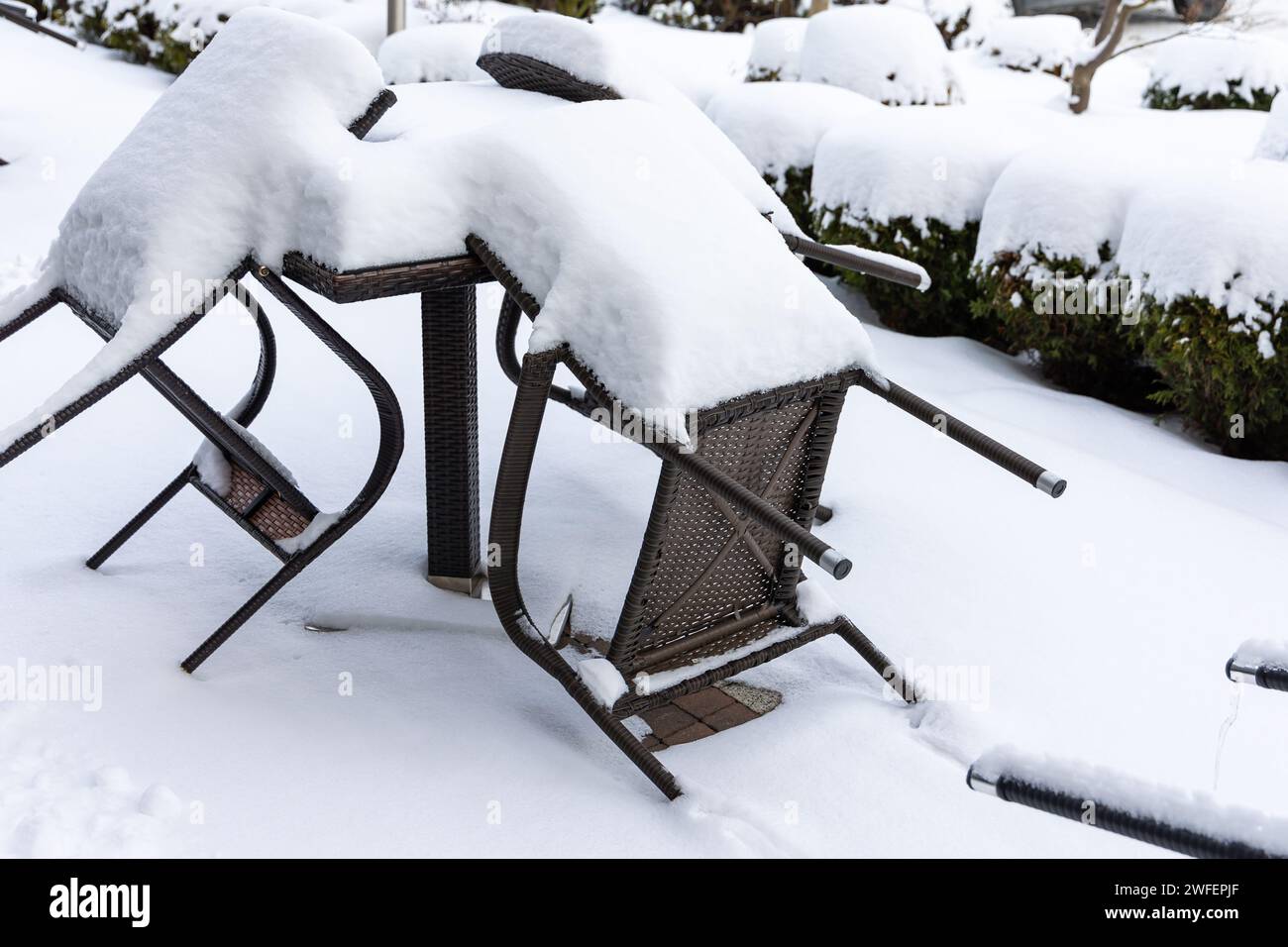 Plastic chairs and a garden table covered with a thick layer of snow ...