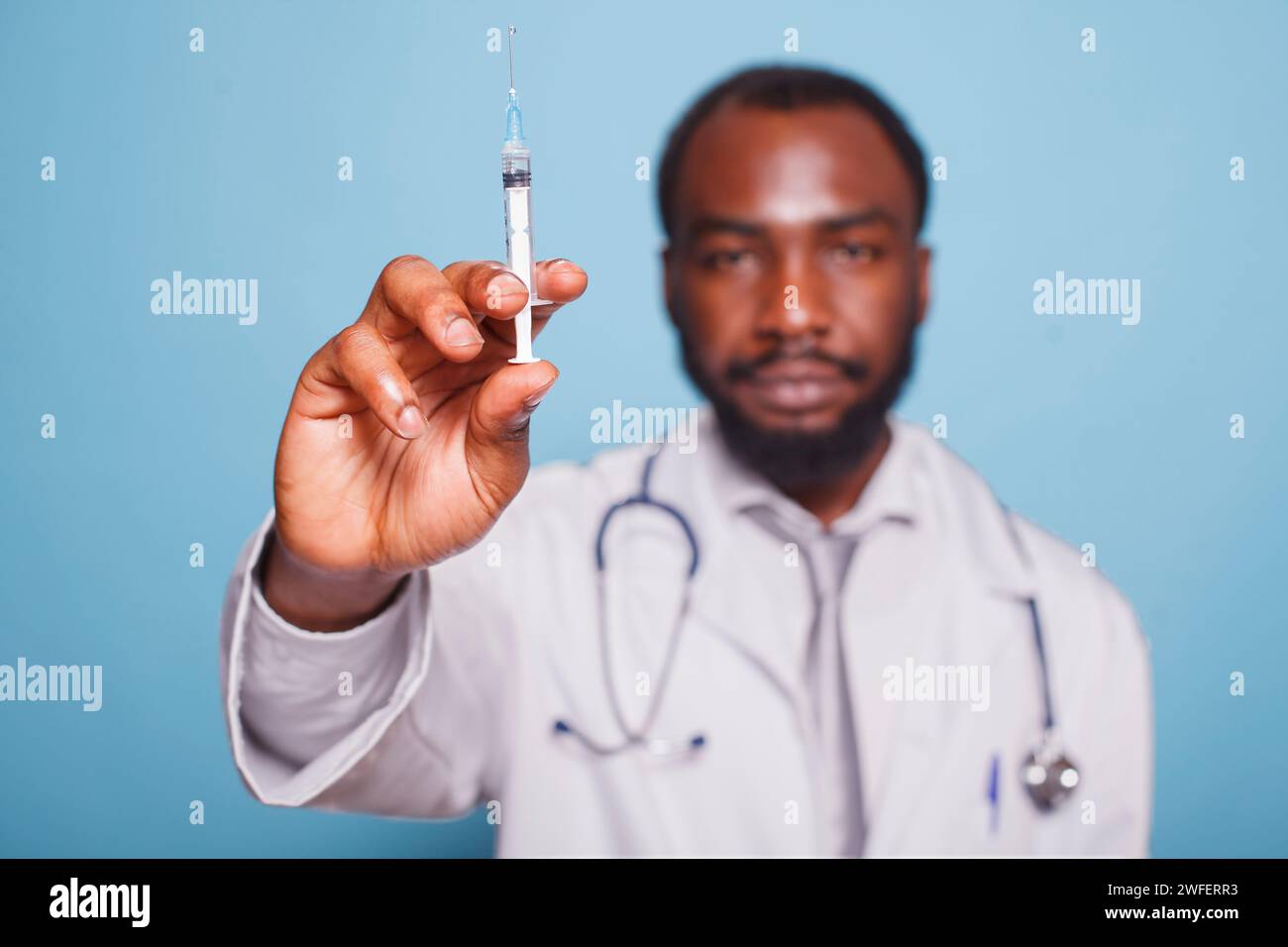 Close-up of doctor wearing white lab coat holding a syringe with ...