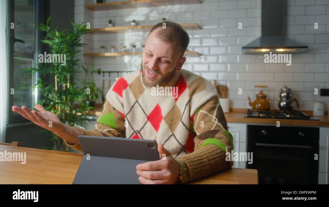 adult man sitting in the kitchen having video call conversation through ...