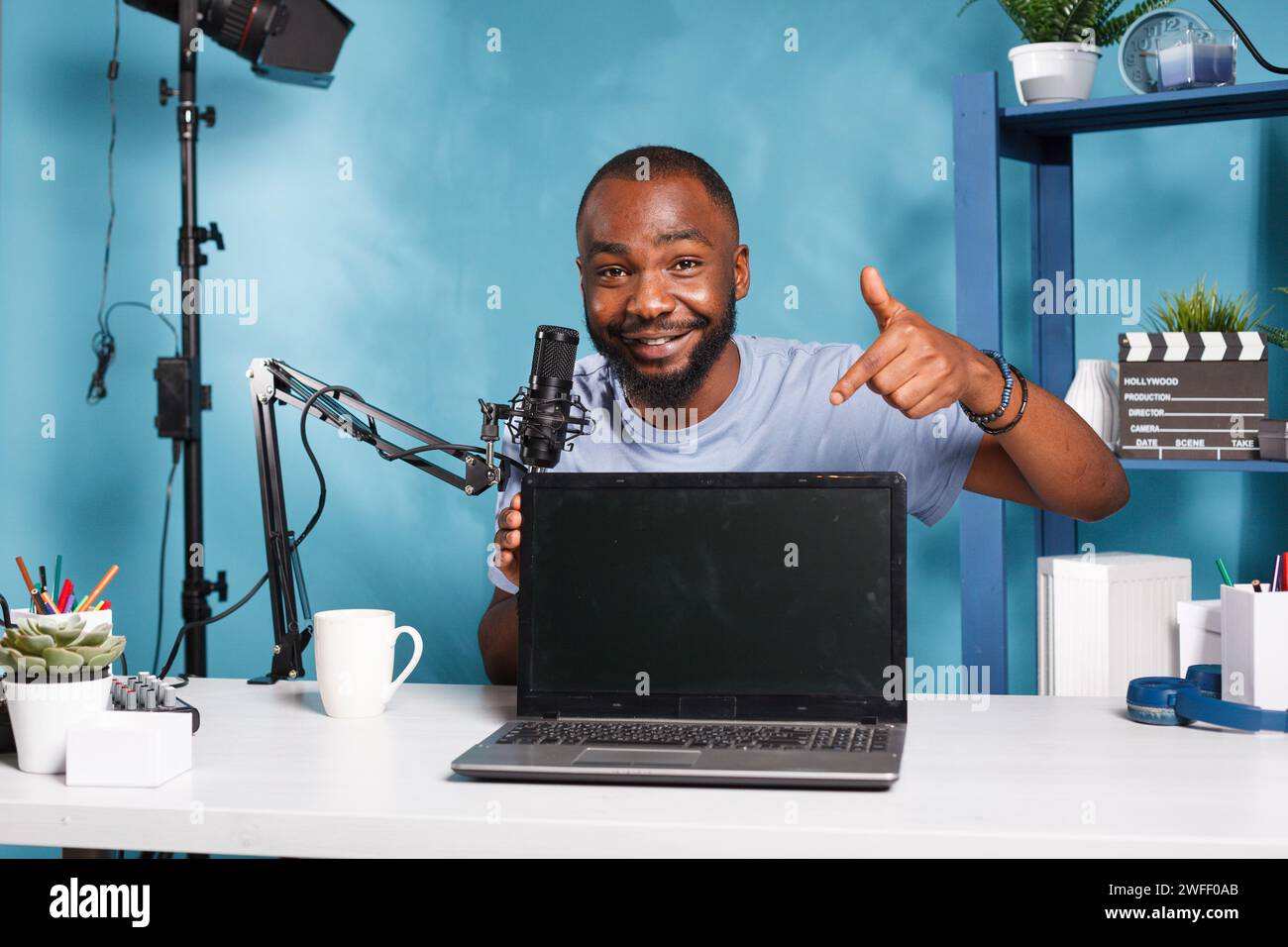 Smiling african american blogger pointing at laptop with black screen ...