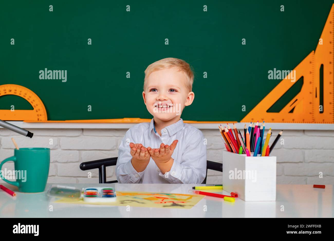 Kids gets ready for school. Friendly child in classroom near blackboard ...