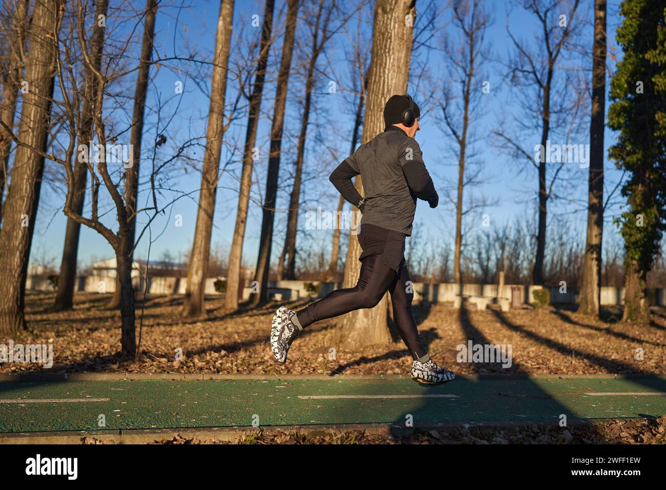 Mature recreational runner with headphones running in the park Stock ...