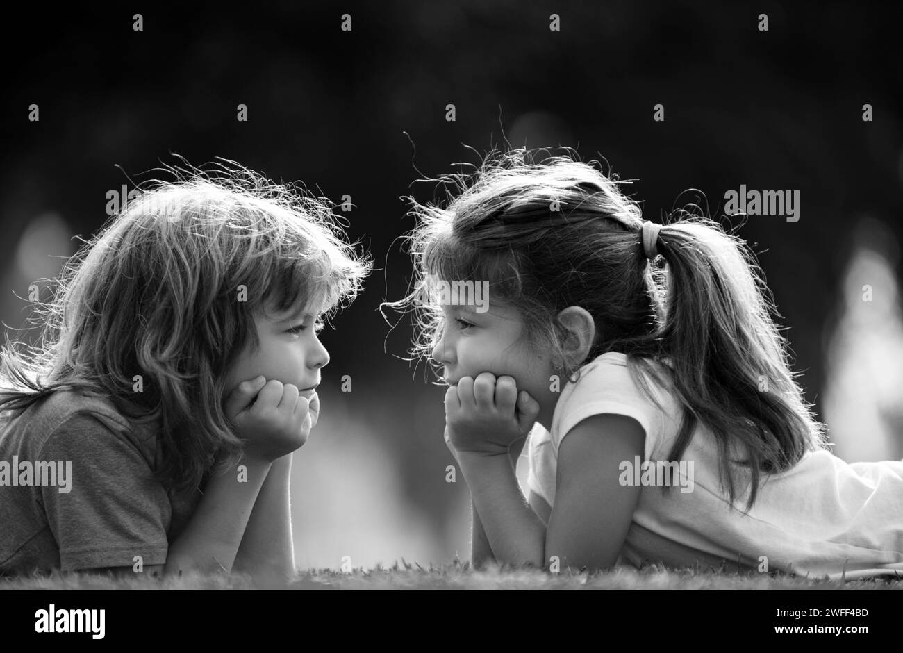 Brother and sister having fun in the park, two cheerful children laying ...