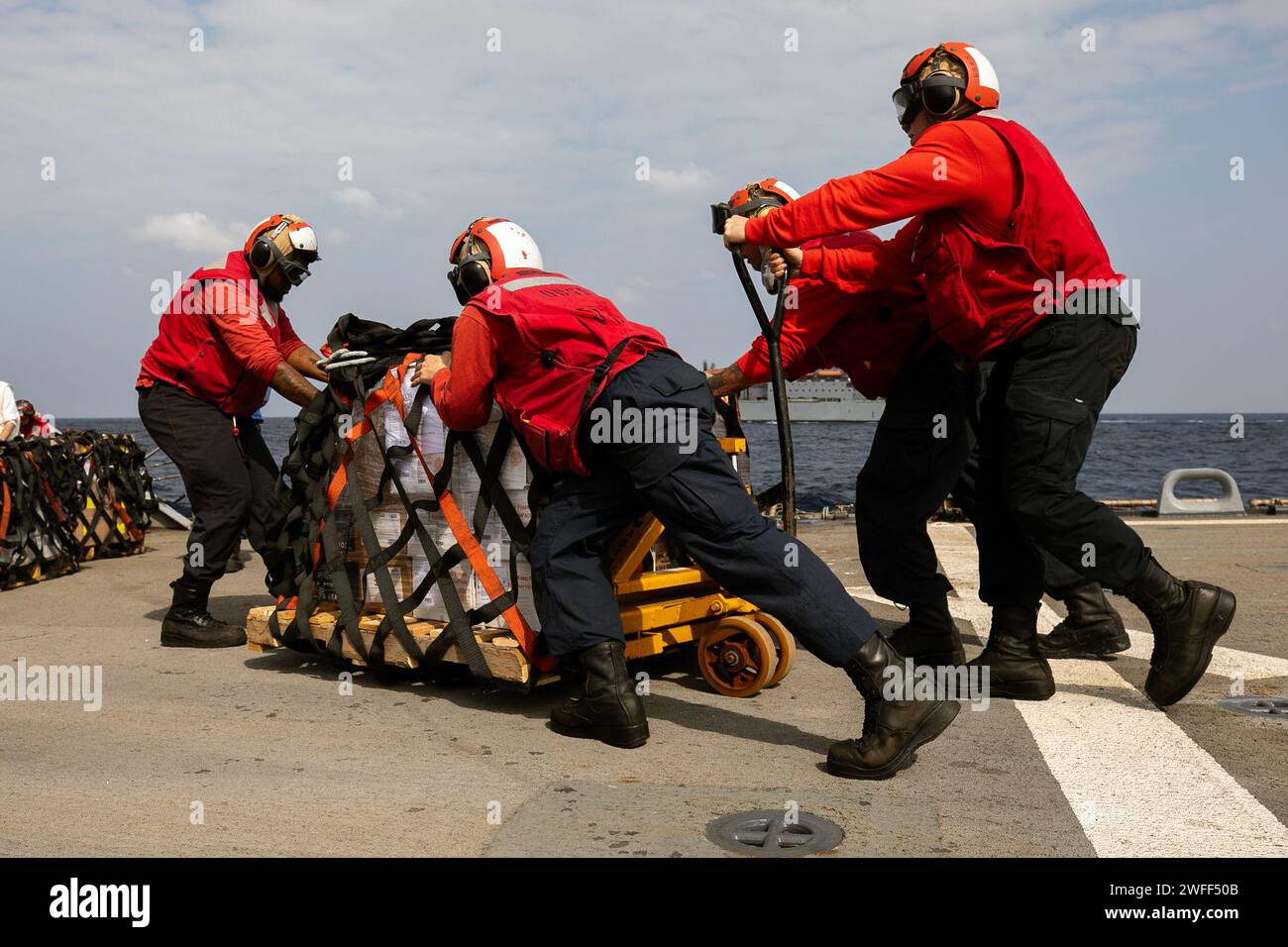 U.S. Navy Sailors move palettes on the flight deck of the guided ...