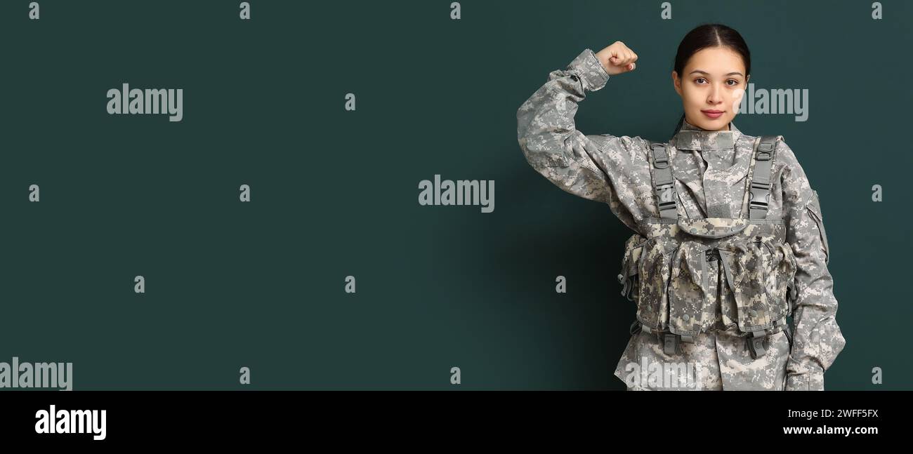 Young female soldier flexing muscles on dark background with space for ...