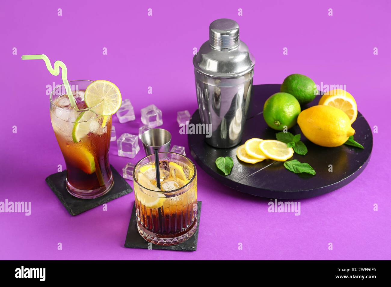 Glasses of tasty Long Island iced tea, shaker and citrus fruits on ...