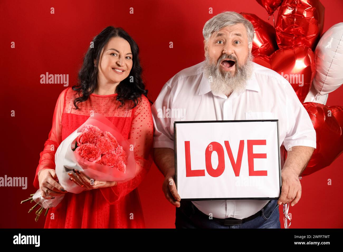 Beautiful shocked mature couple with heart-shaped balloons, bouquet of ...