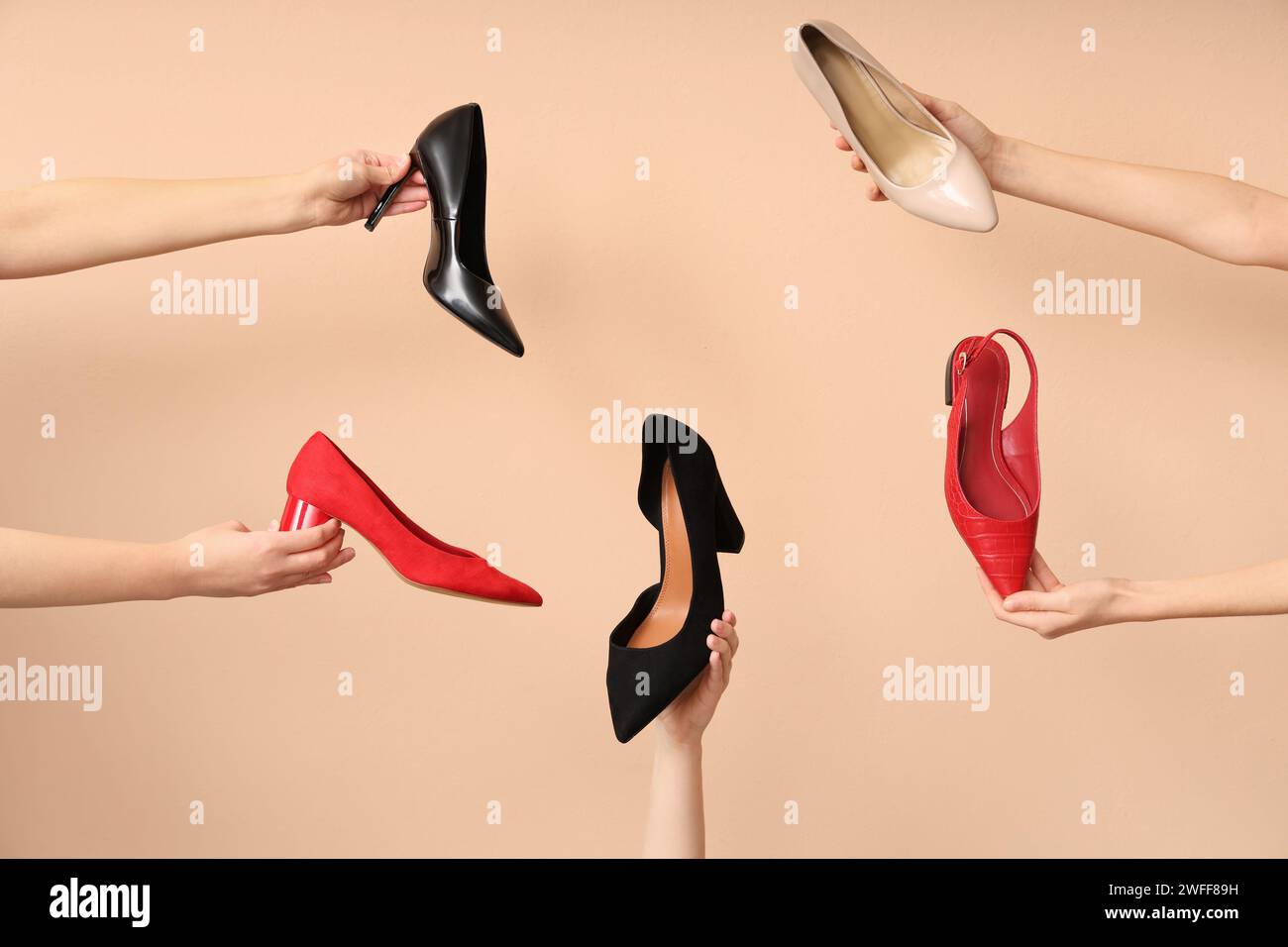 Female hands with different stylish high heel shoes on beige background ...