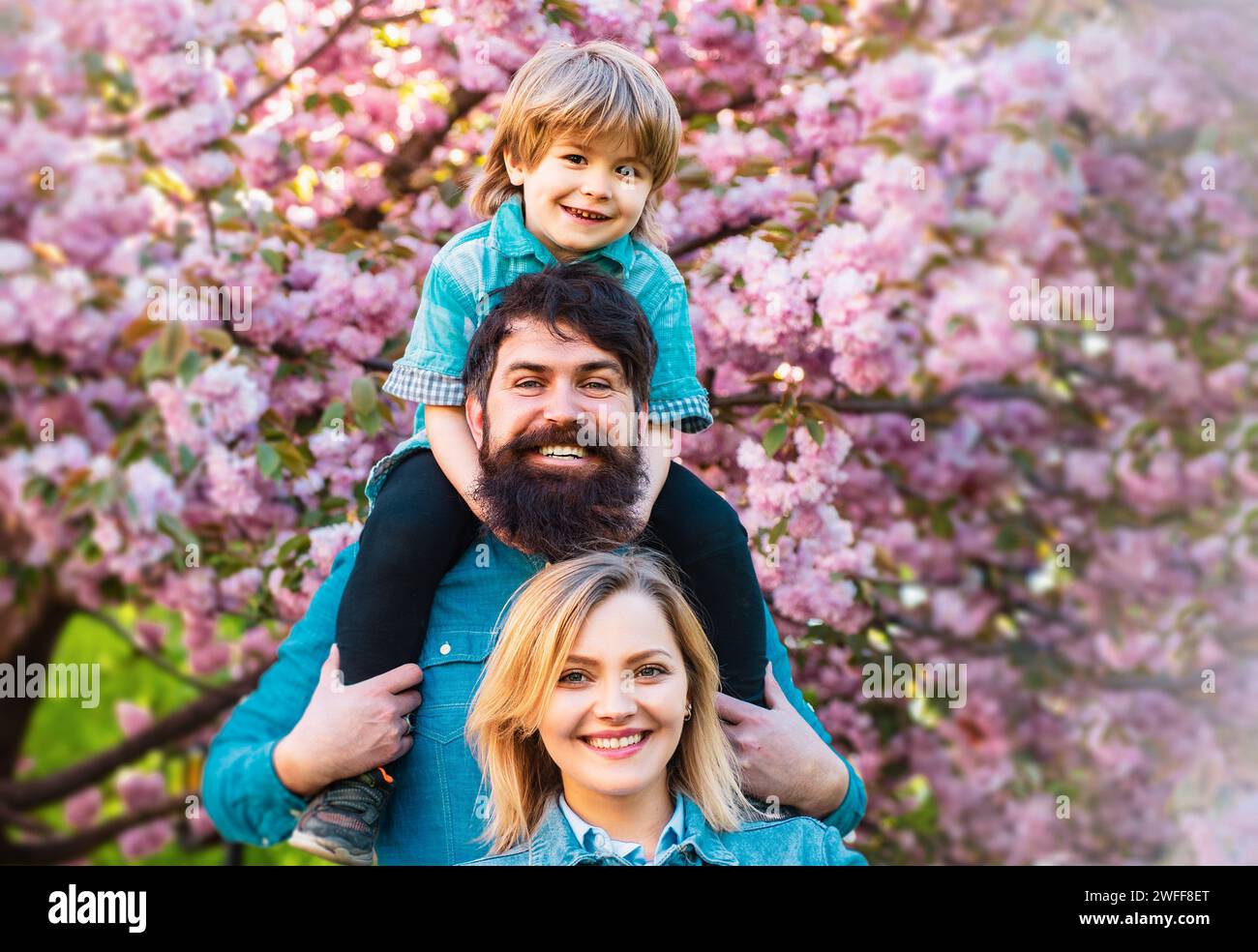 Parents giving child piggybacks in countryside. Mother father and son ...