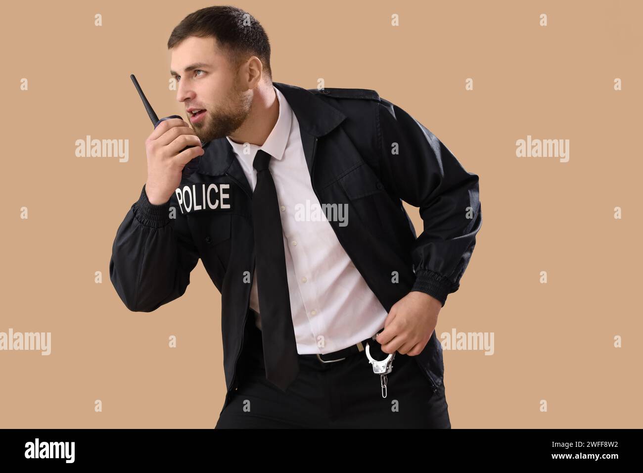 Male police officer with radio transmitter on beige background Stock ...