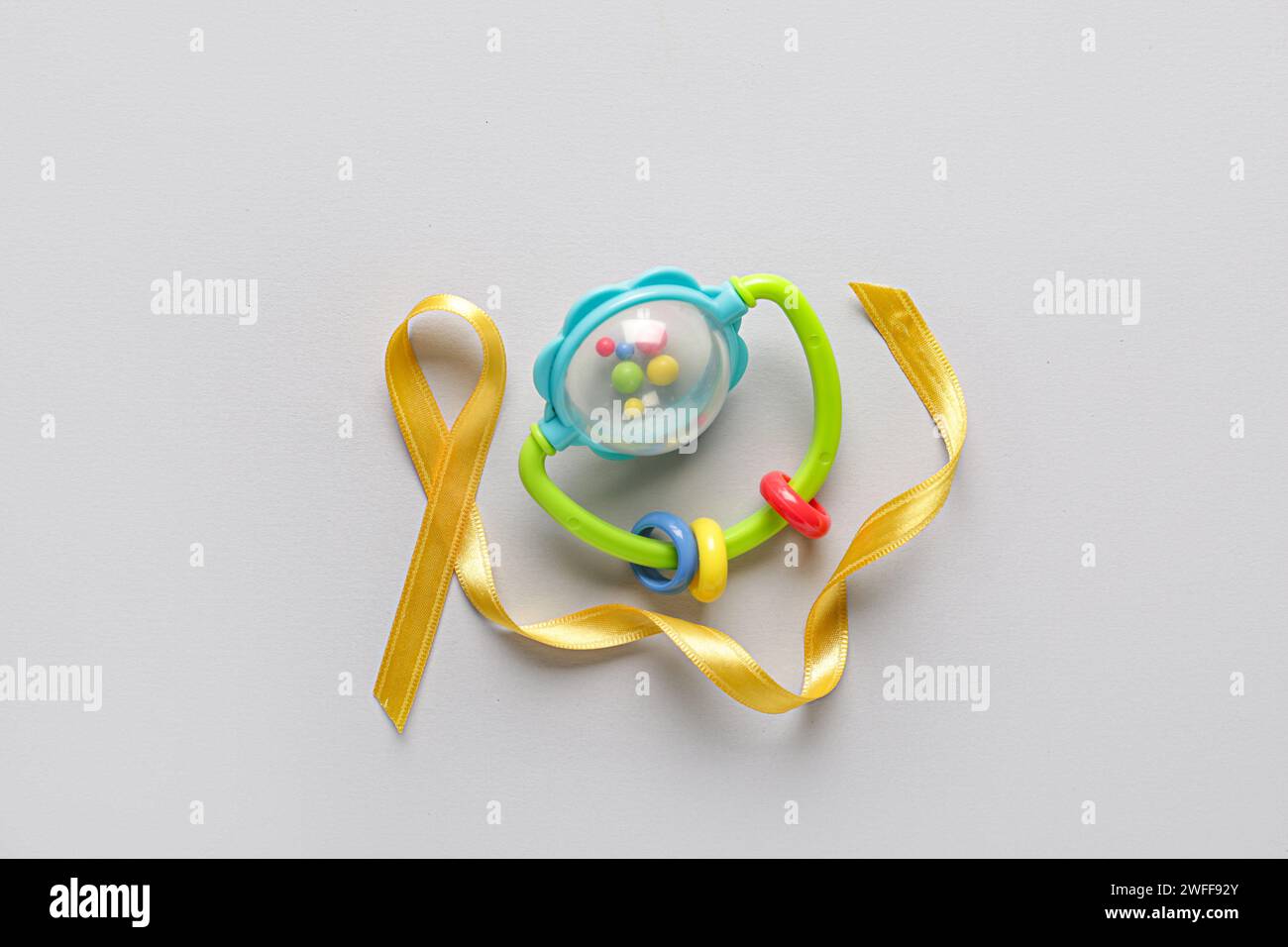 Golden ribbon with baby rattle on white background. Childhood cancer ...