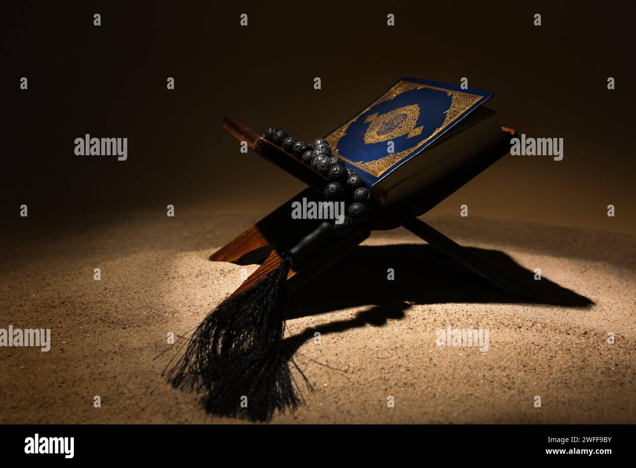 Rehal with Koran and prayer beads for Ramadan on sand against dark ...