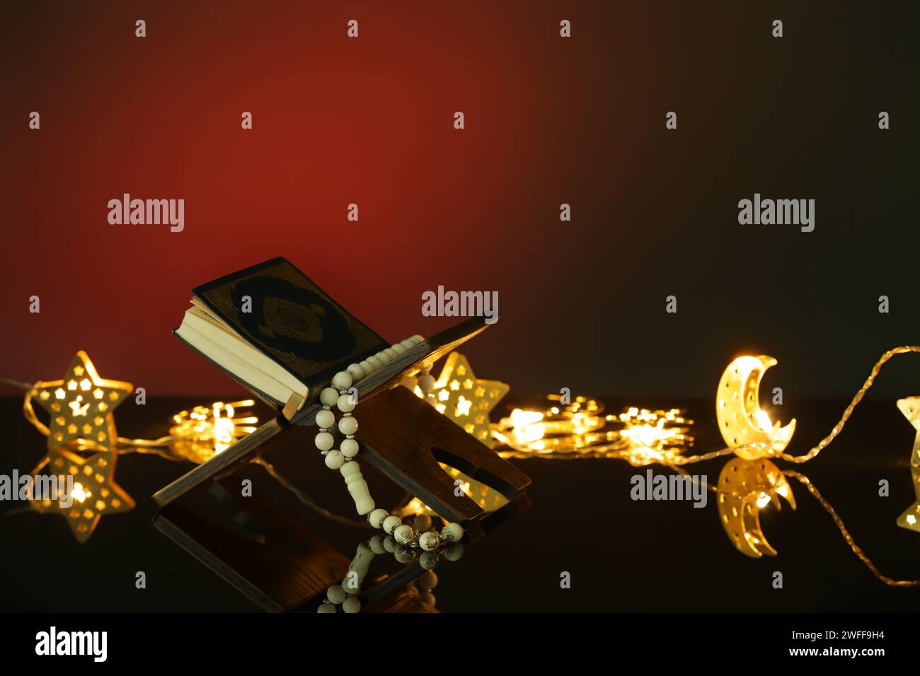 Rehal with Koran, prayer beads and garland for Ramadan on dark red ...