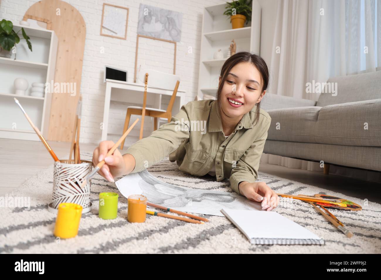 Female Asian artist drawing on floor in workshop Stock Photo - Alamy